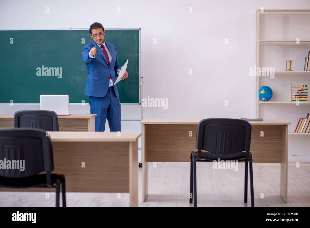 Young teacher in suit in front of green board Stock Photo - Alamy