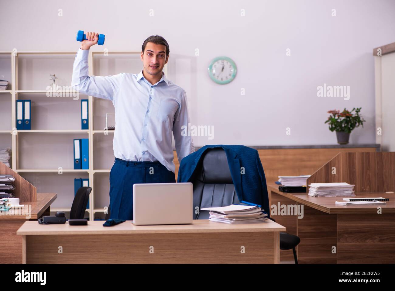 Young employee doing physical exercises at workplace Stock Photo - Alamy