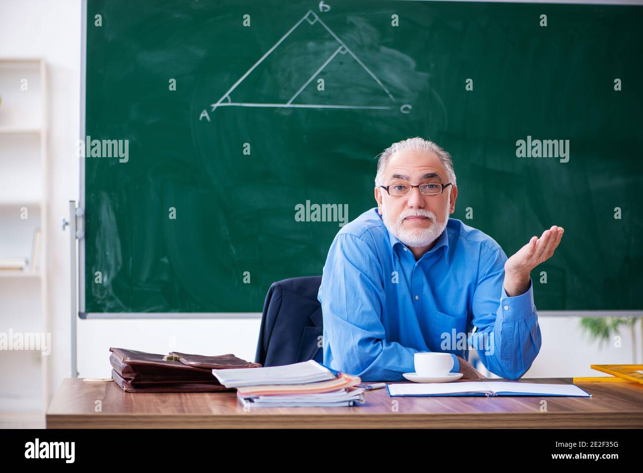 Aged male math teacher in the classroom Stock Photo - Alamy