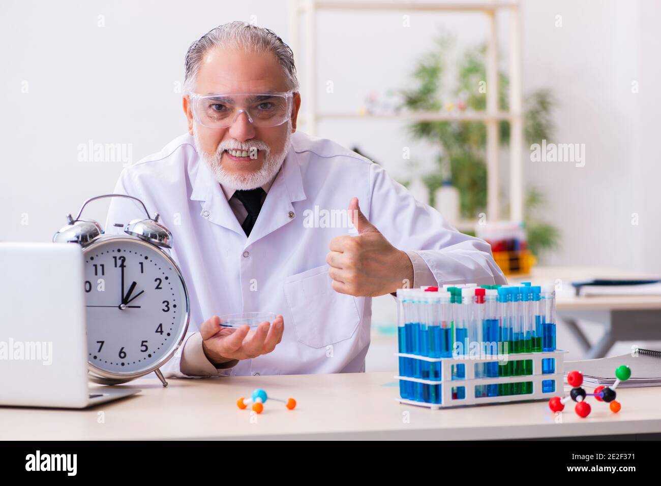Senior male chemist in time management concept Stock Photo - Alamy