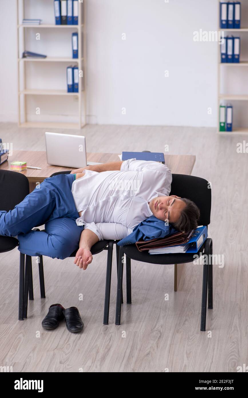 Young employee sleeping in the office on chairs Stock Photo - Alamy