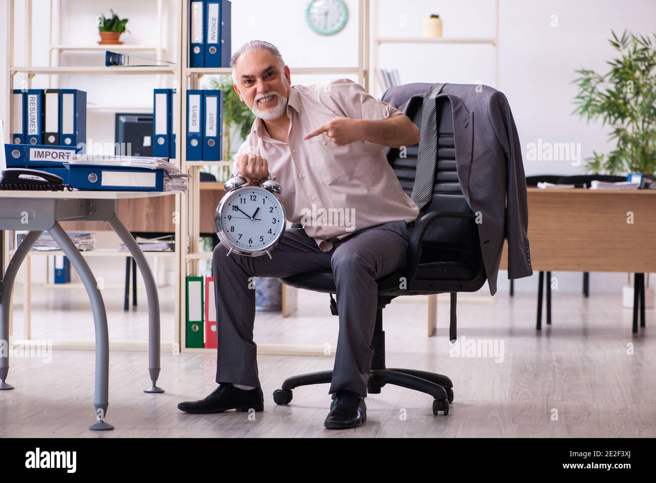 Senior male employee doing physical exercises in time management ...