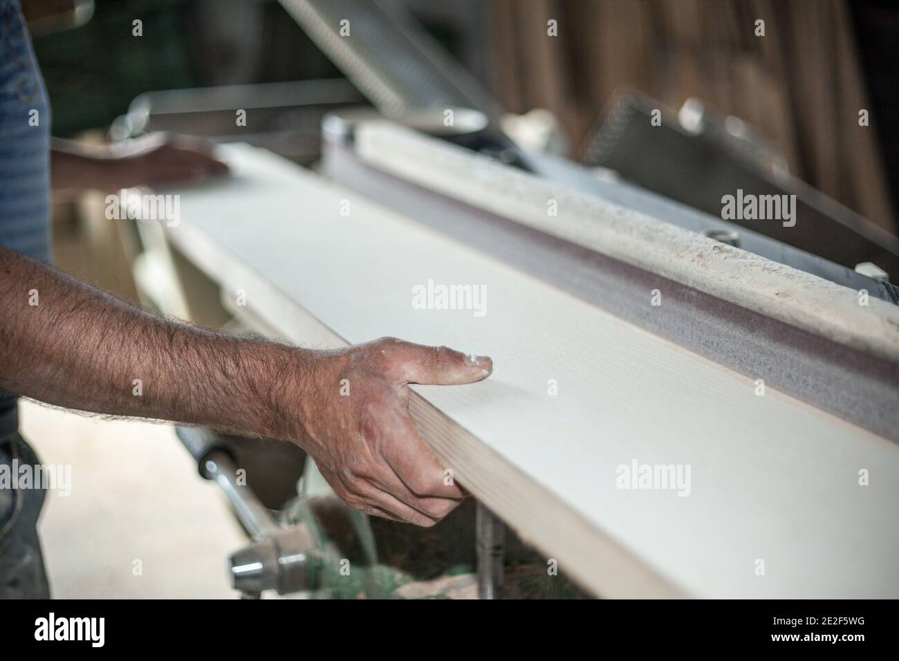 Male making something from a thick wood in a factory with a big machine ...