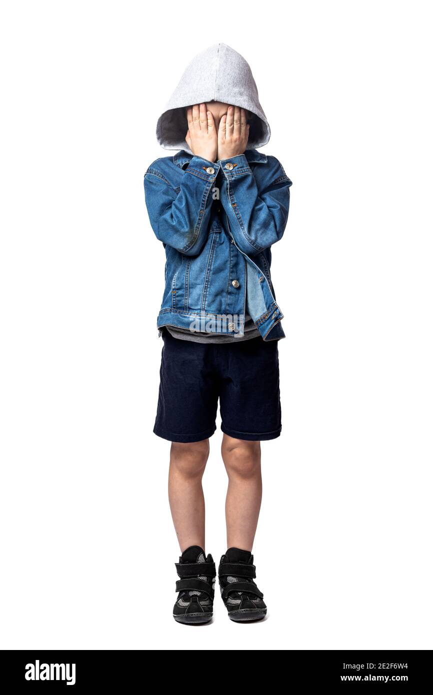 Portrait of a sad boy in a denim jacket, covers his face with his hands ...