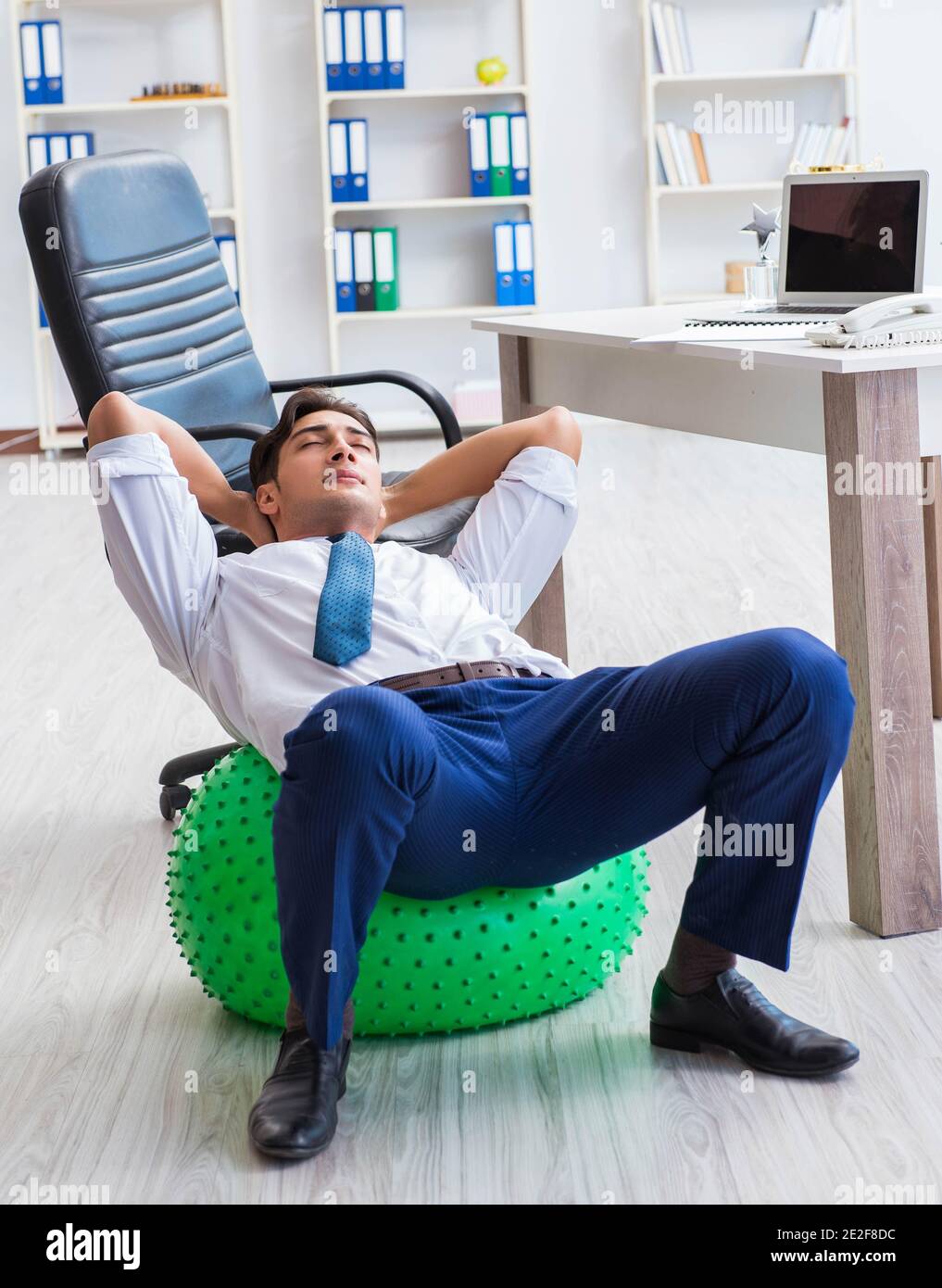The young businessman doing sports stretching at workplace Stock Photo ...