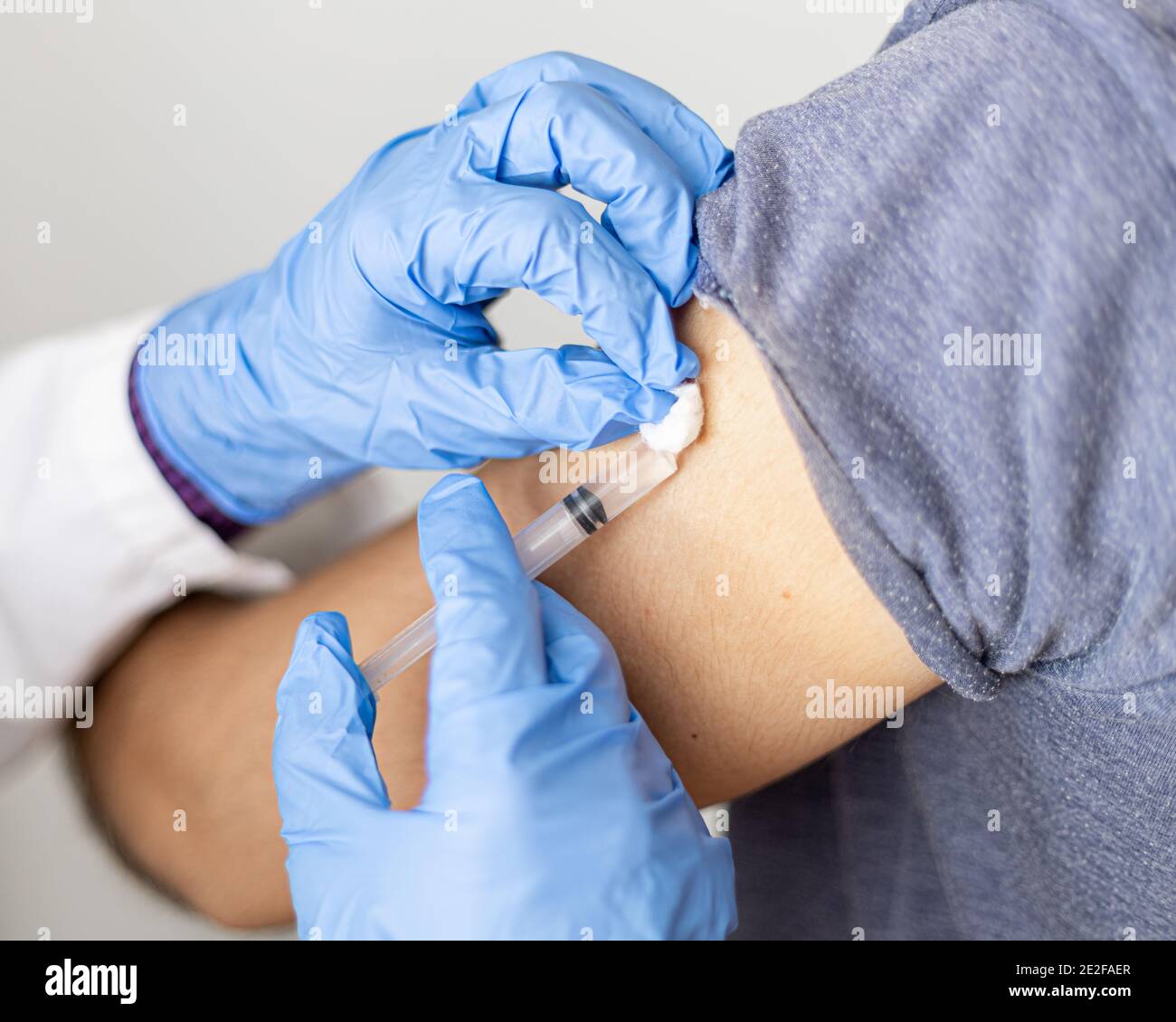 Doctor with blue gloves giving injections from arm to the man Stock ...