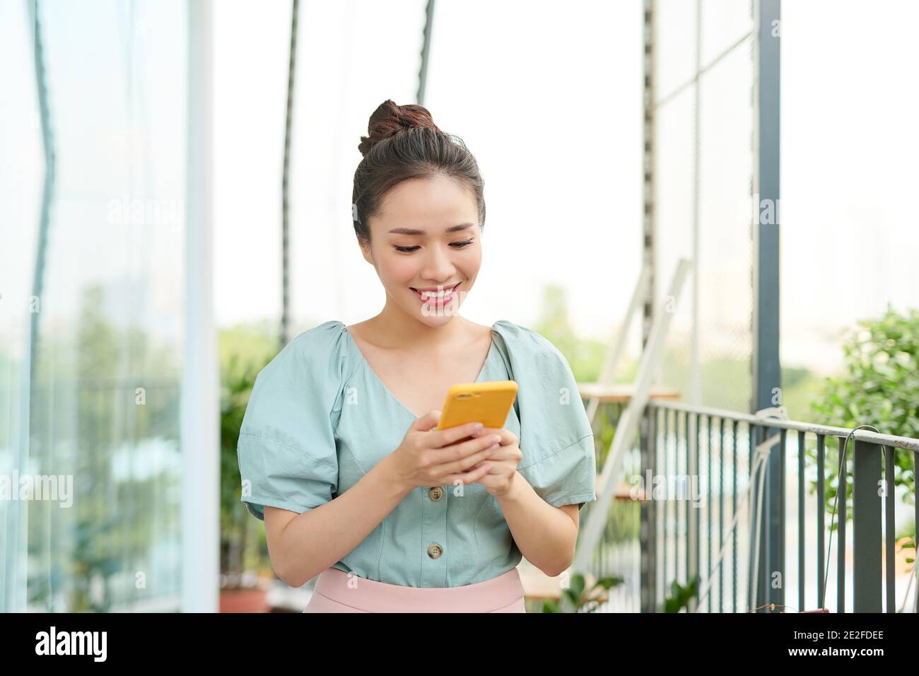 Young Asian woman enjoying nature and using phone on the balcony Stock ...