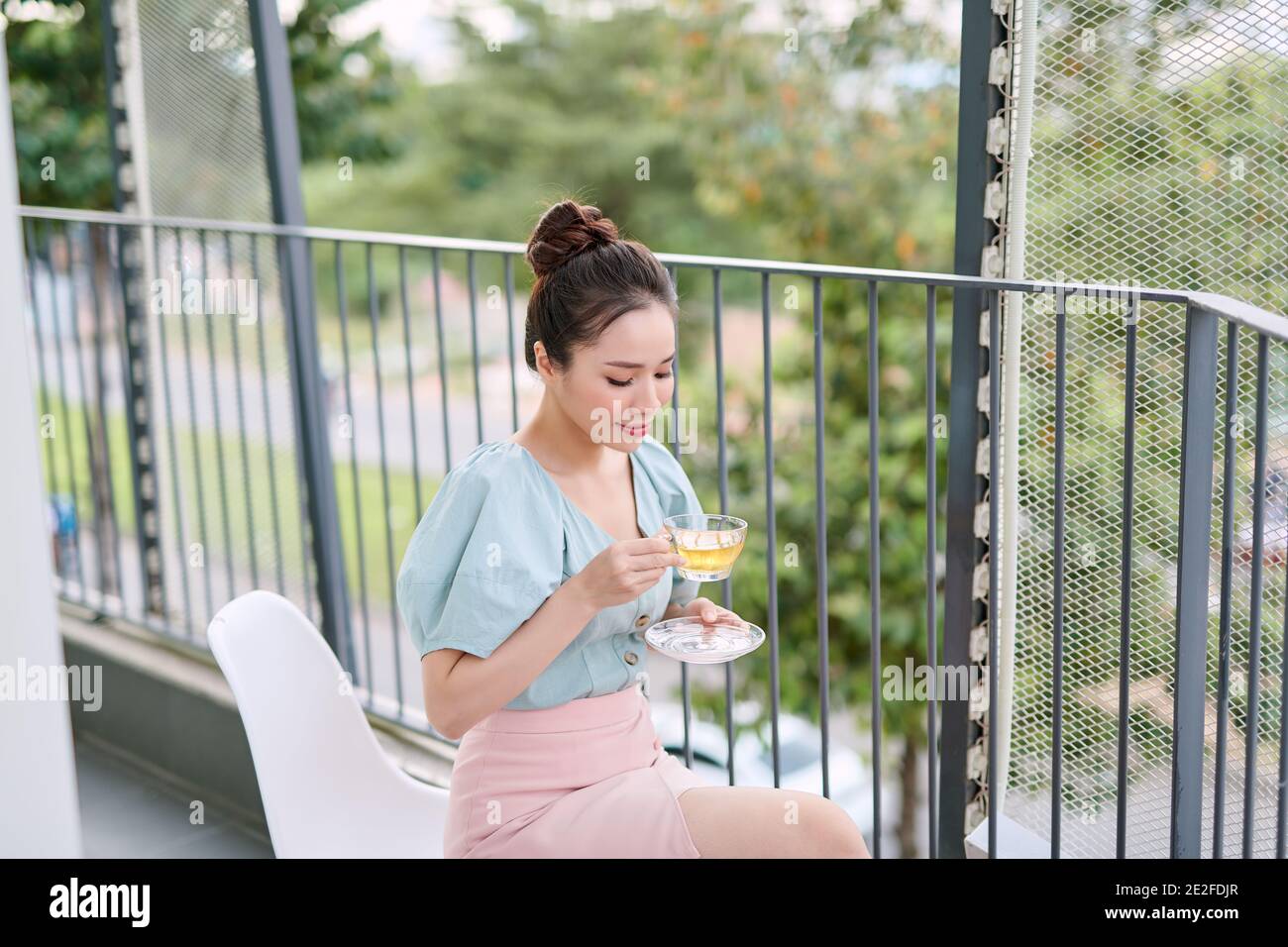 Elegant young Asian woman drinking tea at the balcony. Relaxing ...