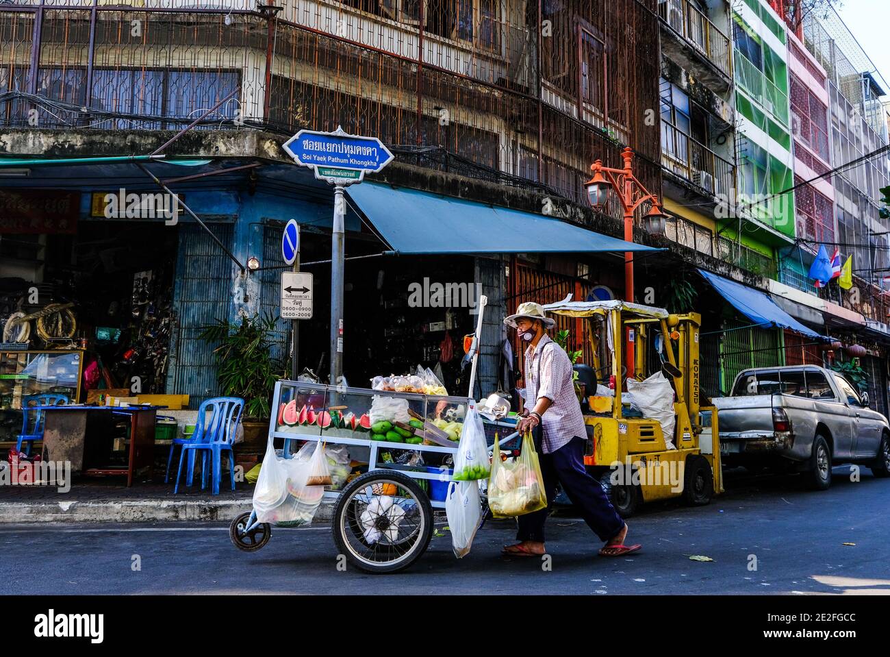 A mobile fruit vendor pushes his cart around the Talat Noi area of ...