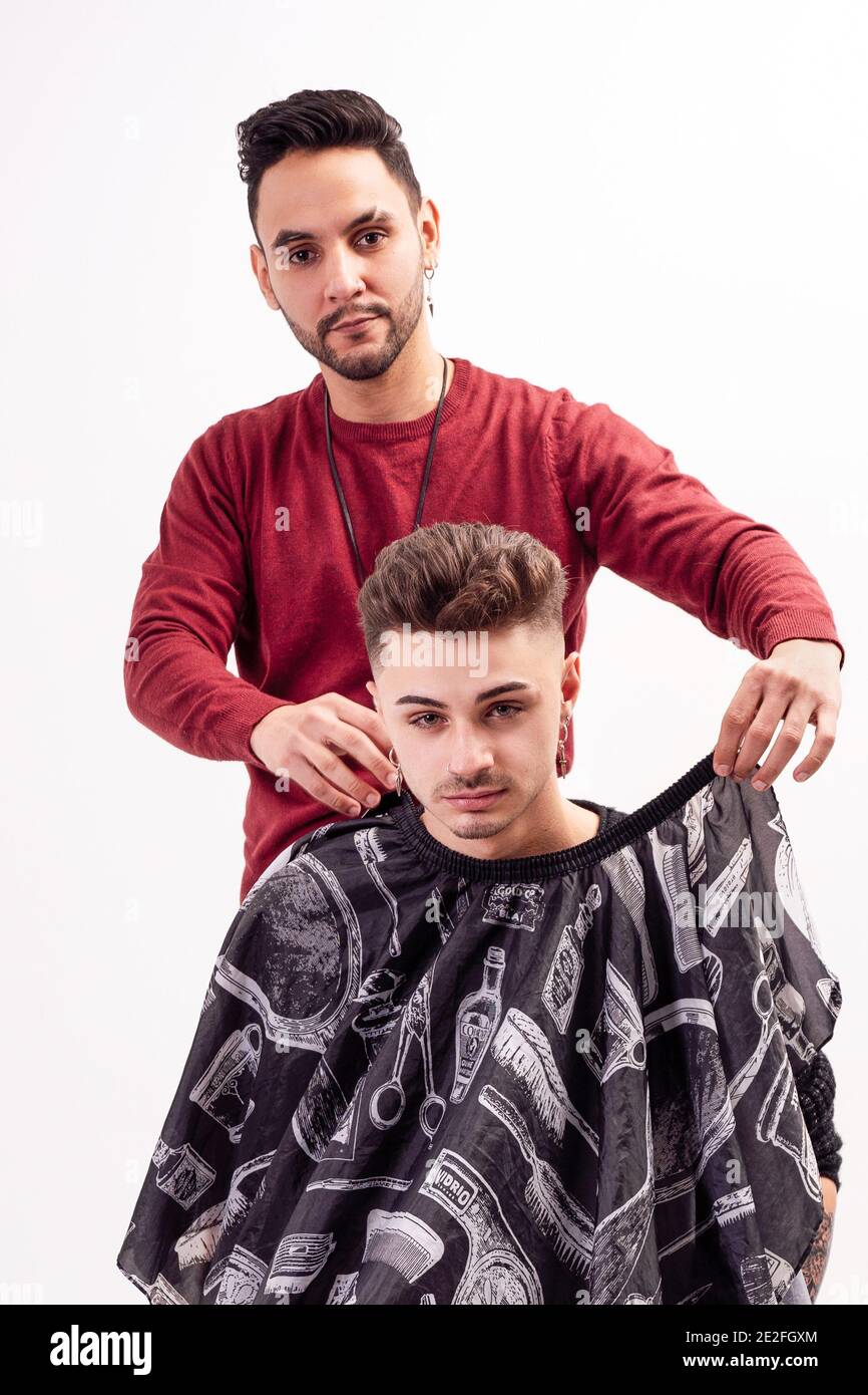Vertical shot of a barber putting apron to client on white background ...