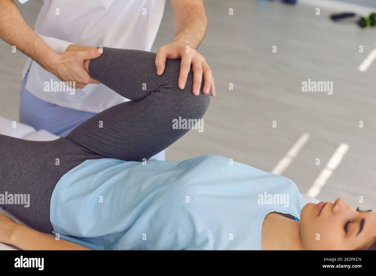 Young woman patient lying and getting procedure of knee and leg joints ...