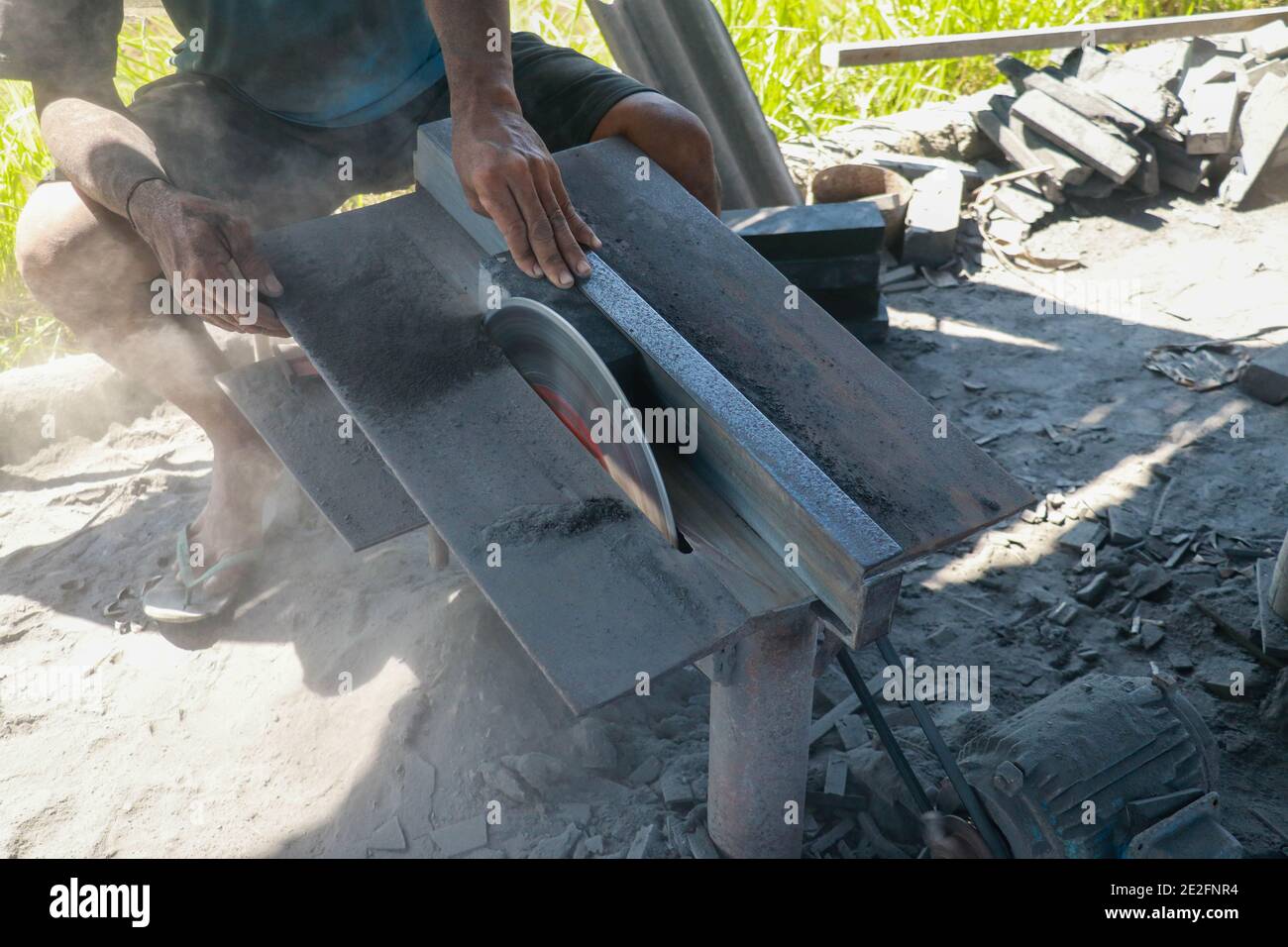 Man uses stone cutter to cut through black stone Stock Photo - Alamy