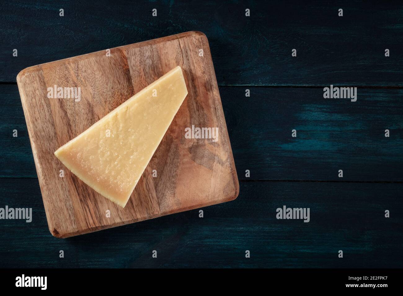 Parmesan cheese, overhead shot on a dark blue background with a place ...