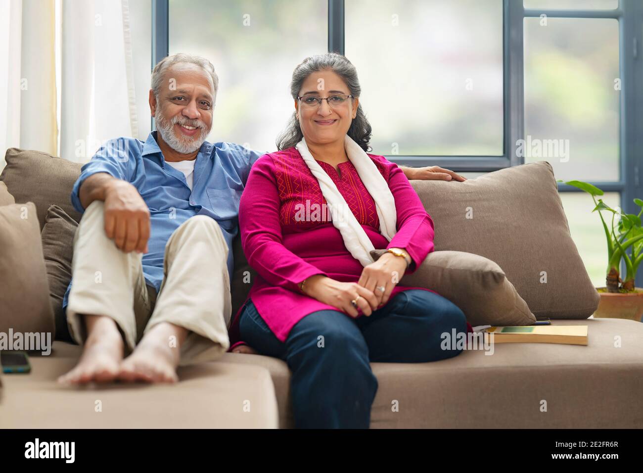 A HAPPY OLD COUPLE SITTING TOGETHER ON SOFA AND LOOKING AT CAMERA Stock ...
