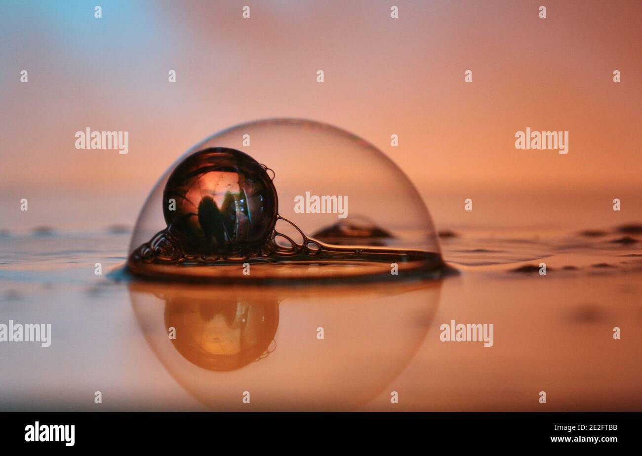 Small reflective crystal ball inside of a bubble on a smooth wet ...