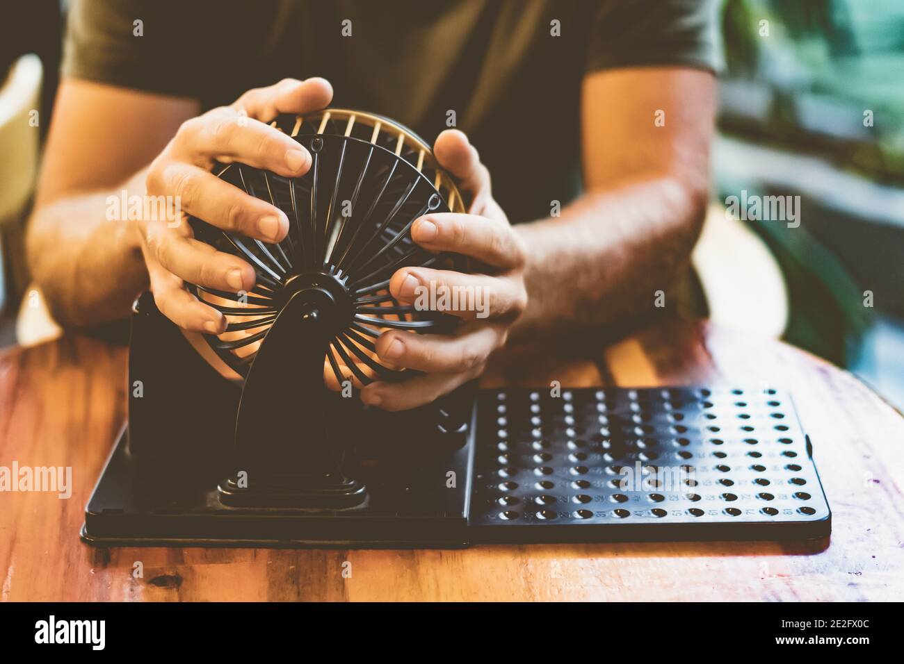 Young man hands hold lotto sphere for small balls spin, table loto game ...