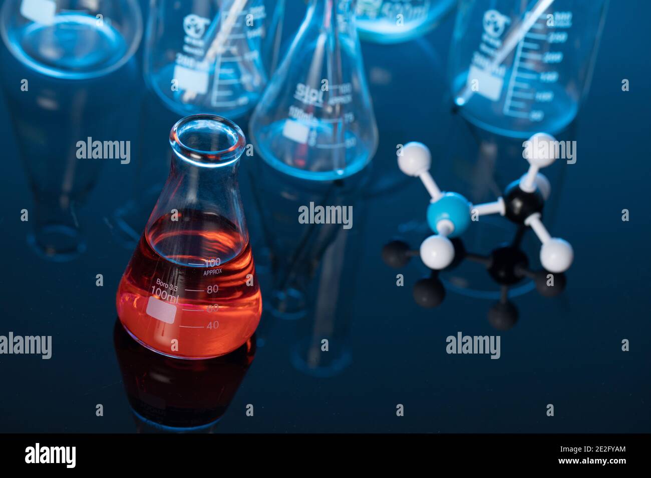 Glass flask with red liquid and a molecule structure on a lab table ...