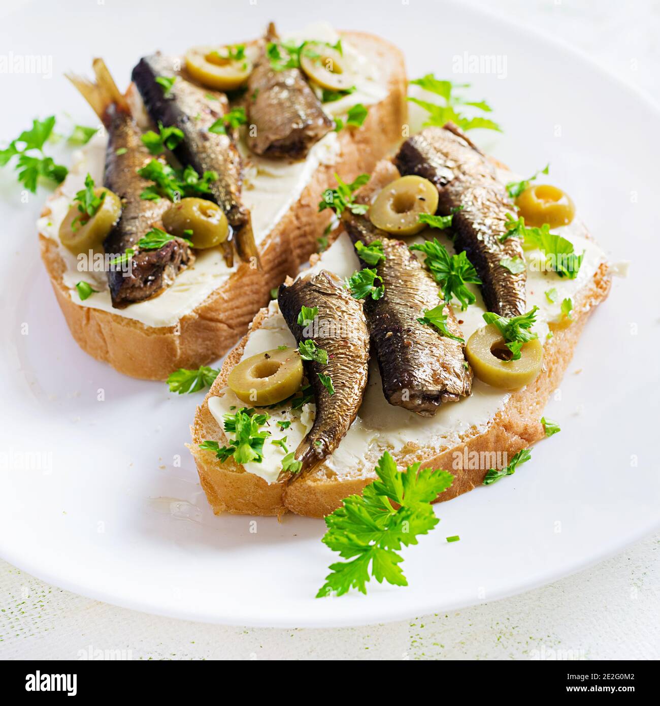 Sandwich - smorrebrod with sprats, green olives and butter on light table. Danish cuisine Stock ...