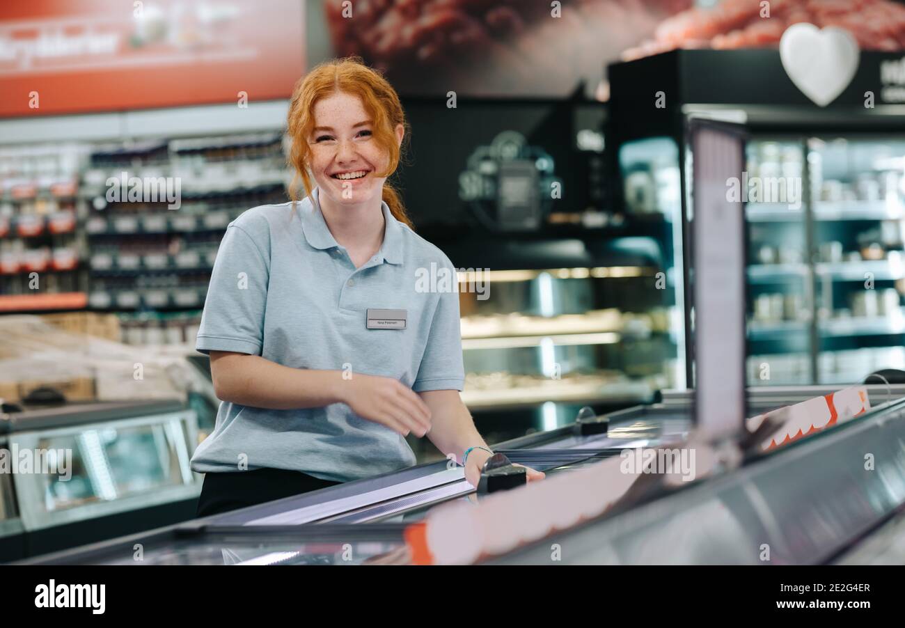 Portrait of a young female trainee working in a supermarket. Woman ...