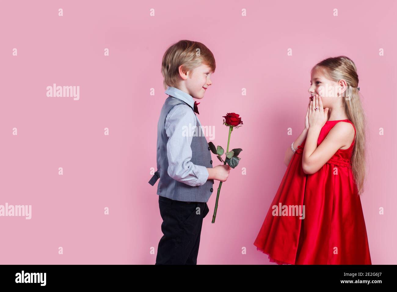 Valentines day surprise. Little boy in love giving cute girl red rose ...