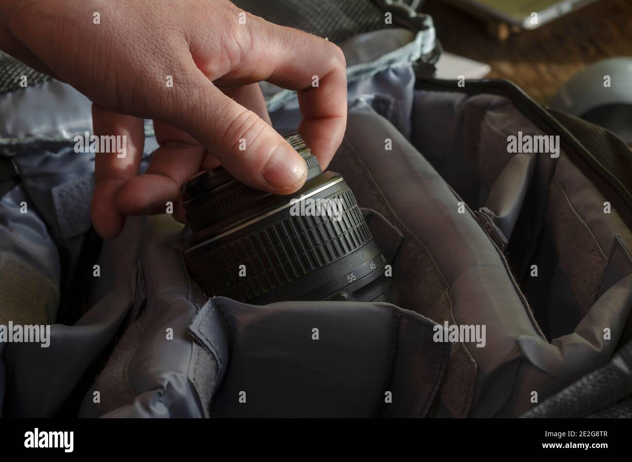 Man's hand places the camera lens in the section of the camera bag ...