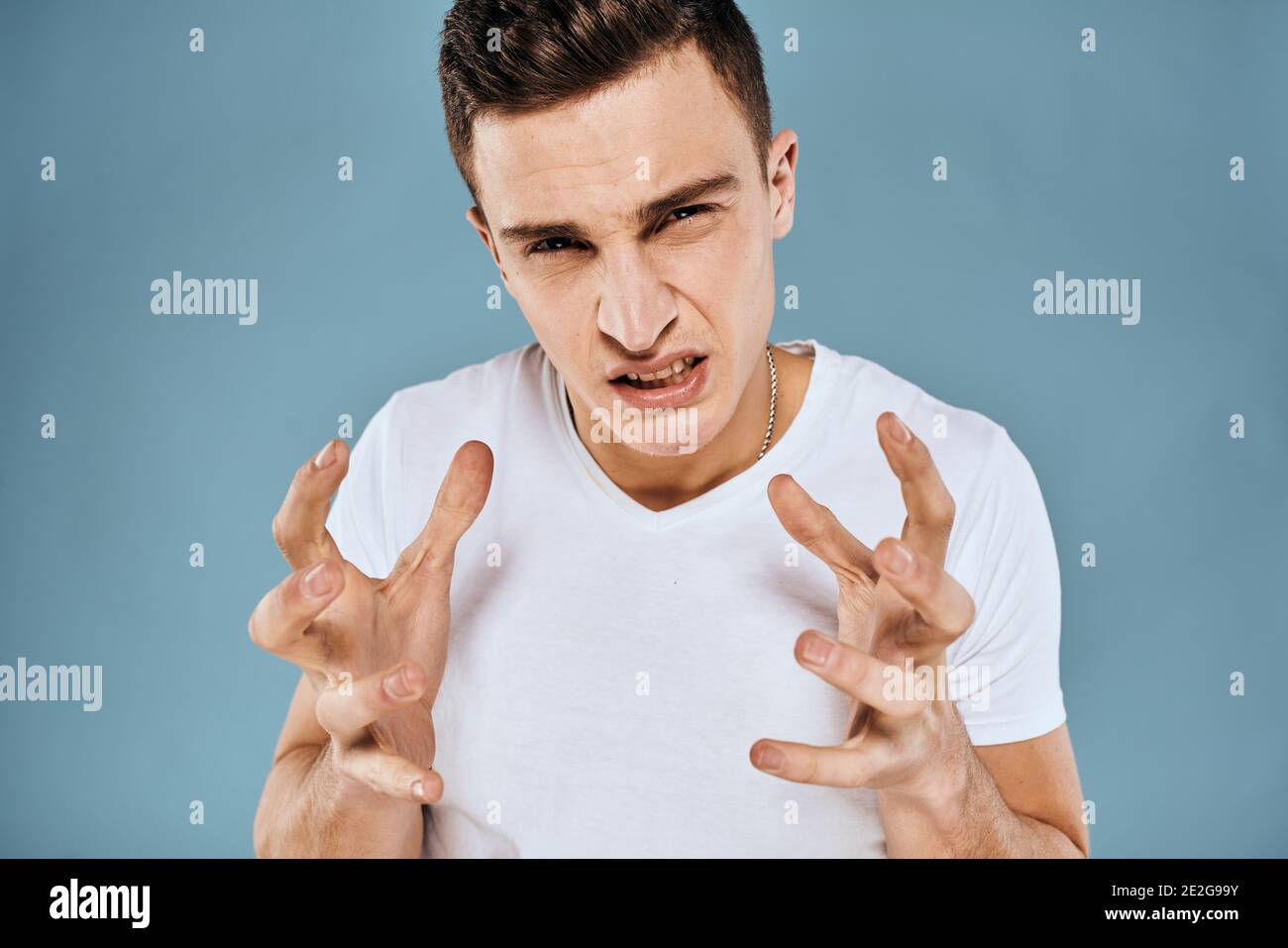 emotional displeased man cropped view white t-shirt blue background ...