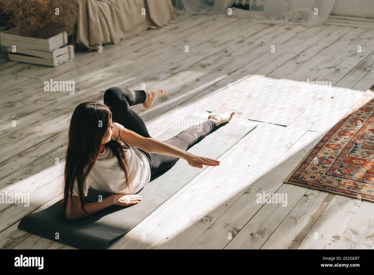 Beautiful brunette fitness woman make stretching exercises indoors at ...