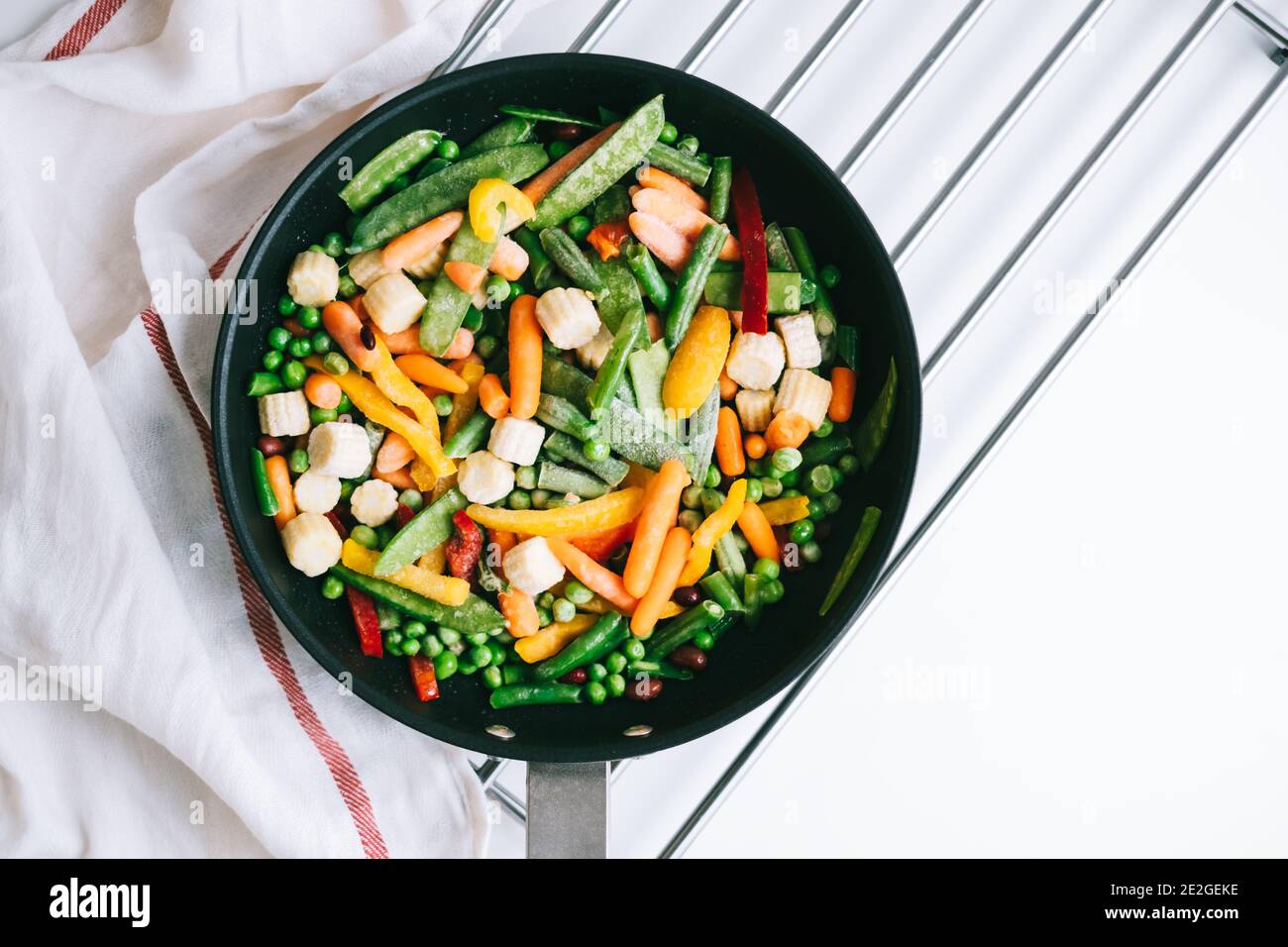 Fresh vegetables mix in a black pan on the white table. Healthy food ...