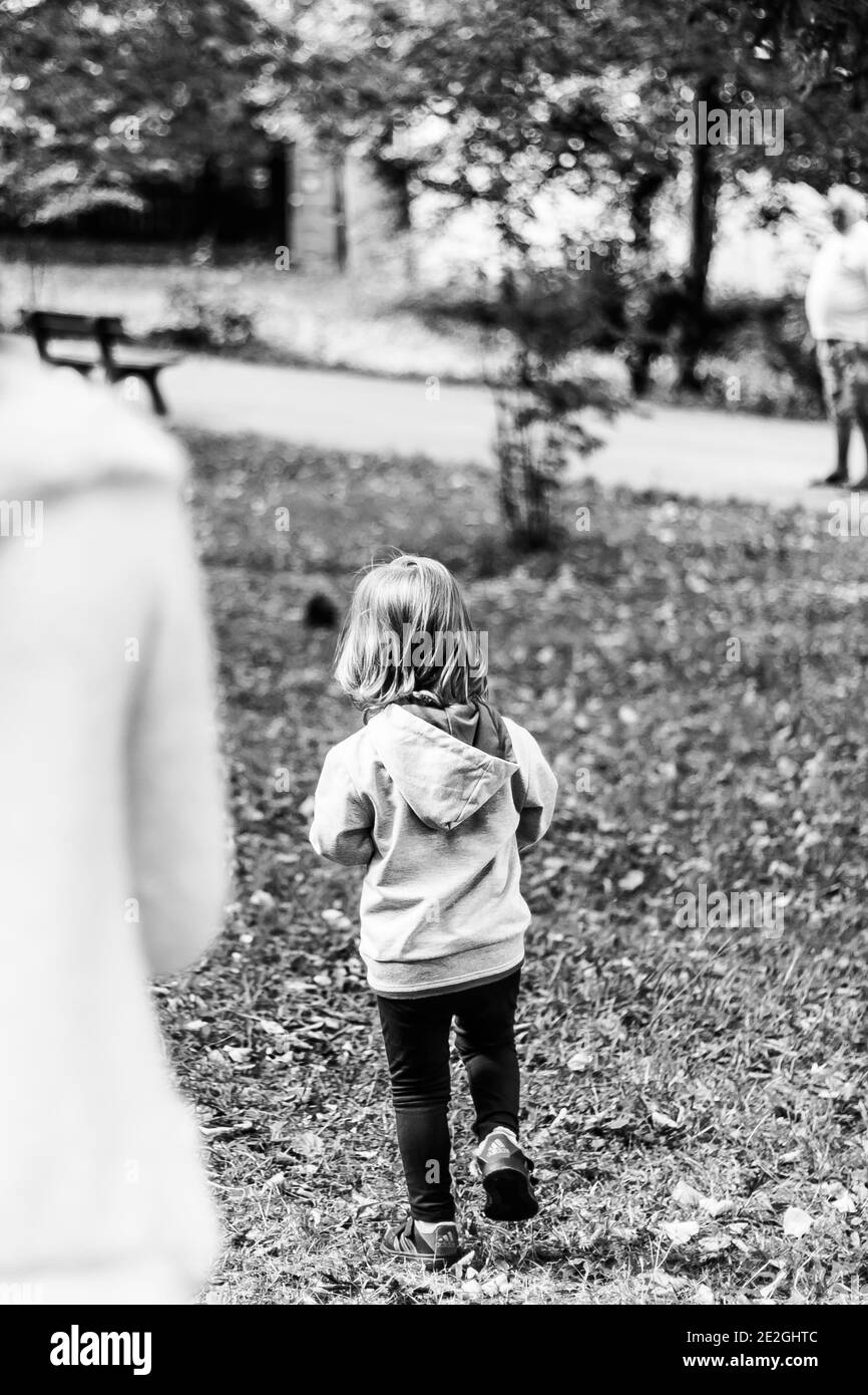 Back view grayscale of a small adorable child walking in the park and ...