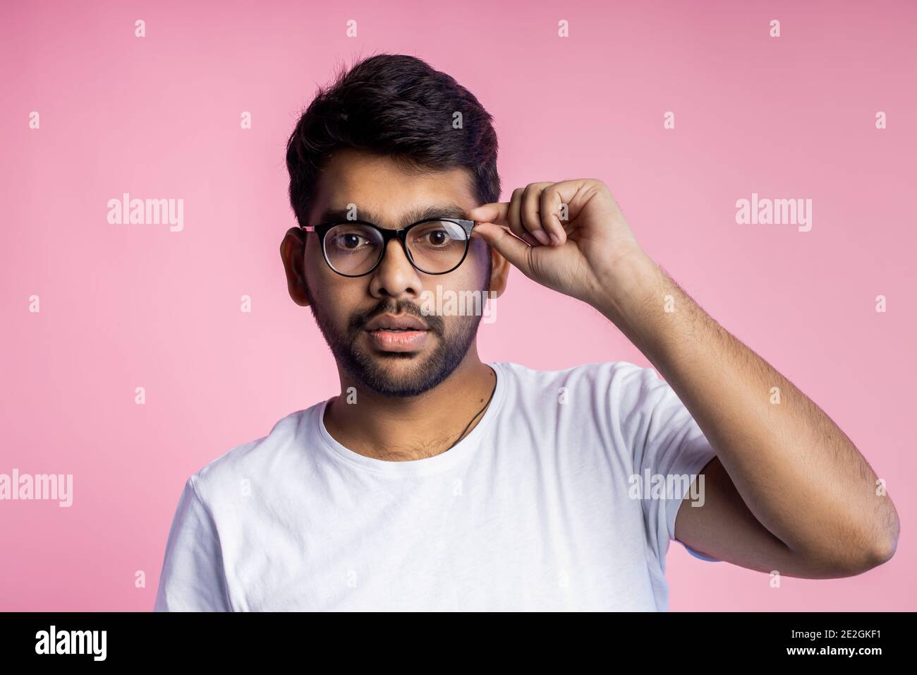 Serious indian young man with bad eyesight, looking thoroughly through ...