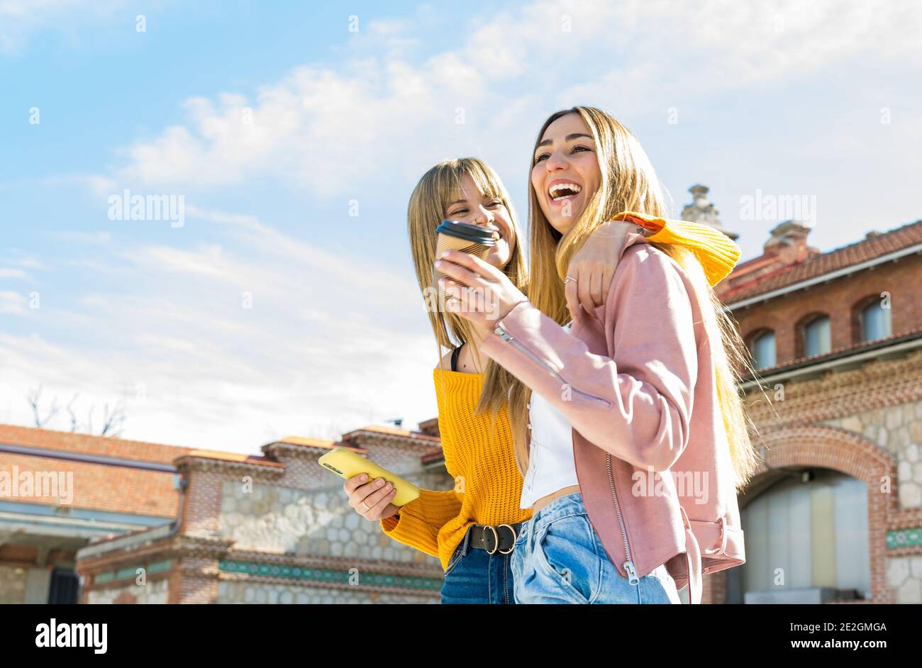 Two happy friends hug each other on the street as they walk and have a ...