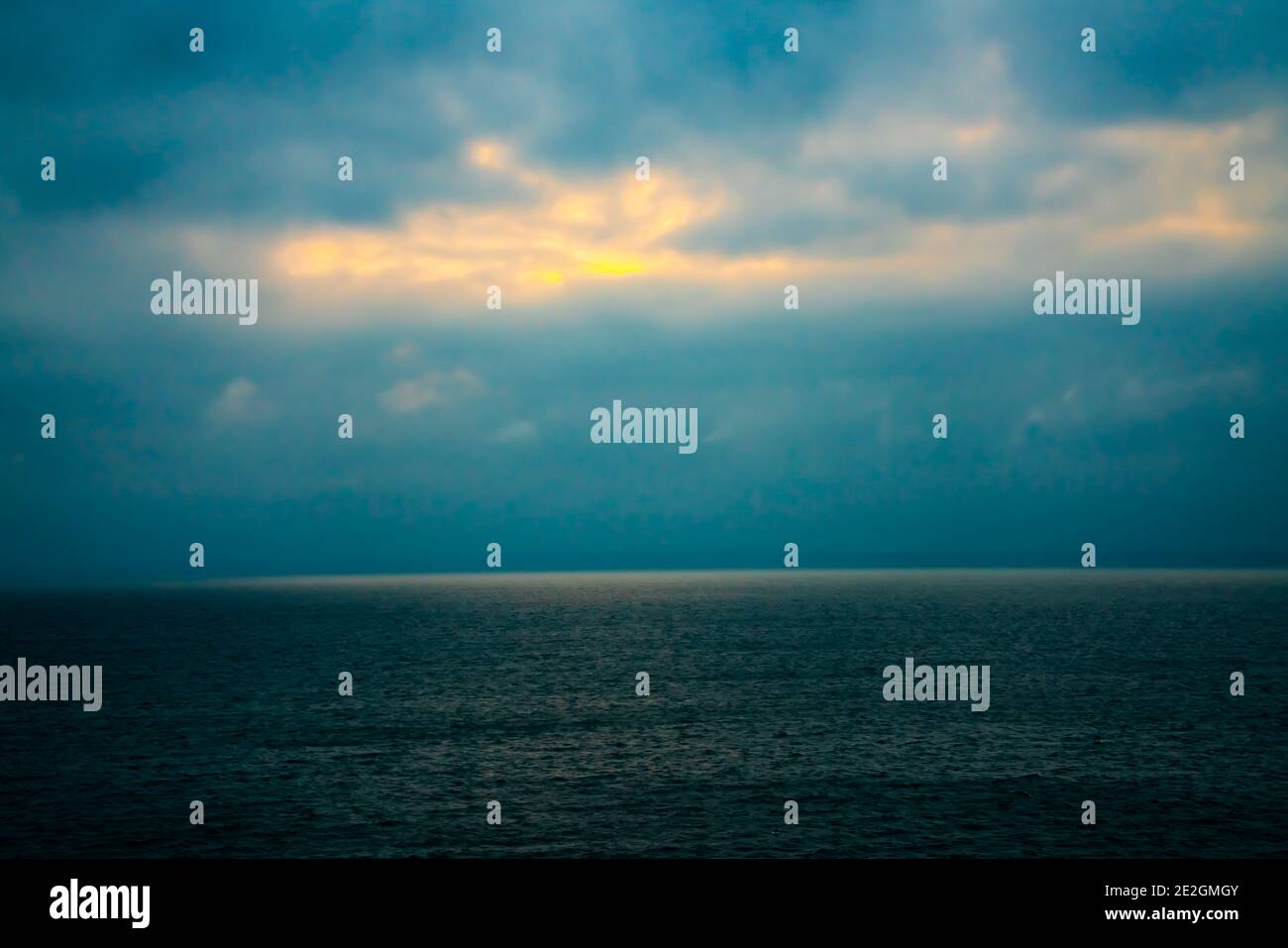 Sunlight breaking through dark gloomy clouds at sea Stock Photo - Alamy