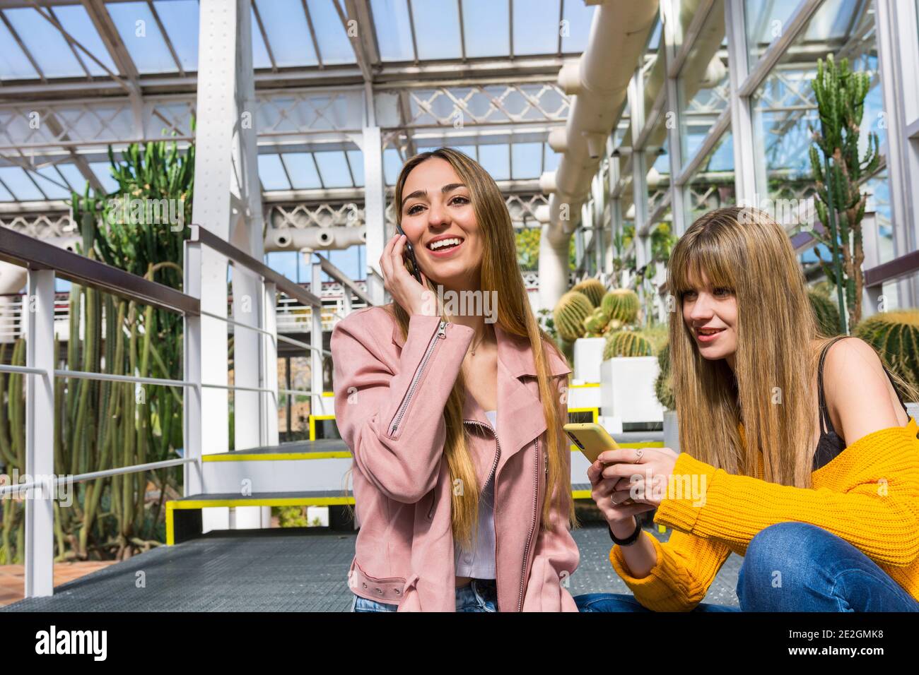 Two friends interacting with their mobile phone while talking and ...