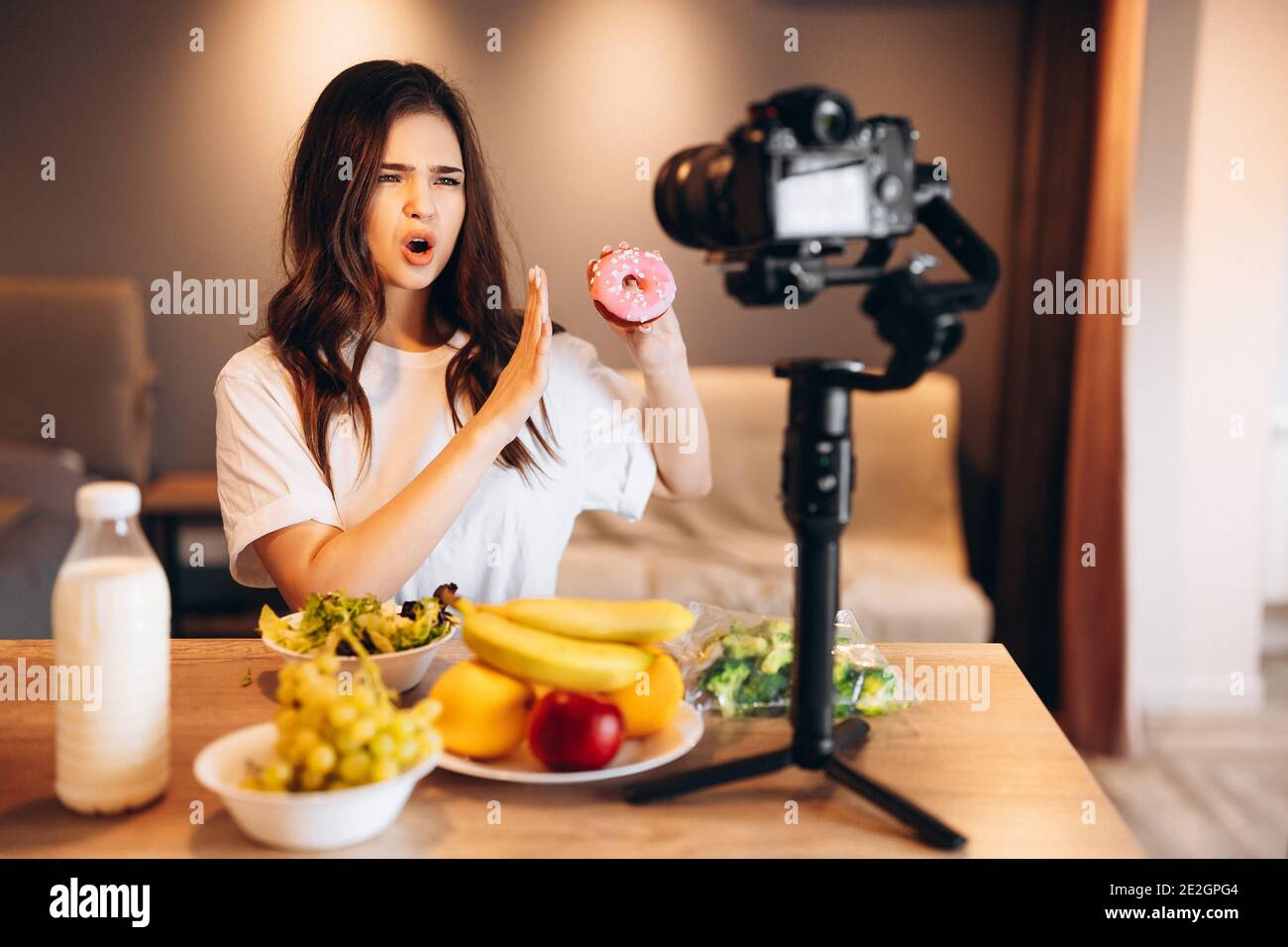 Healthy food blogger young female cooking fresh vegan salad of fruits ...