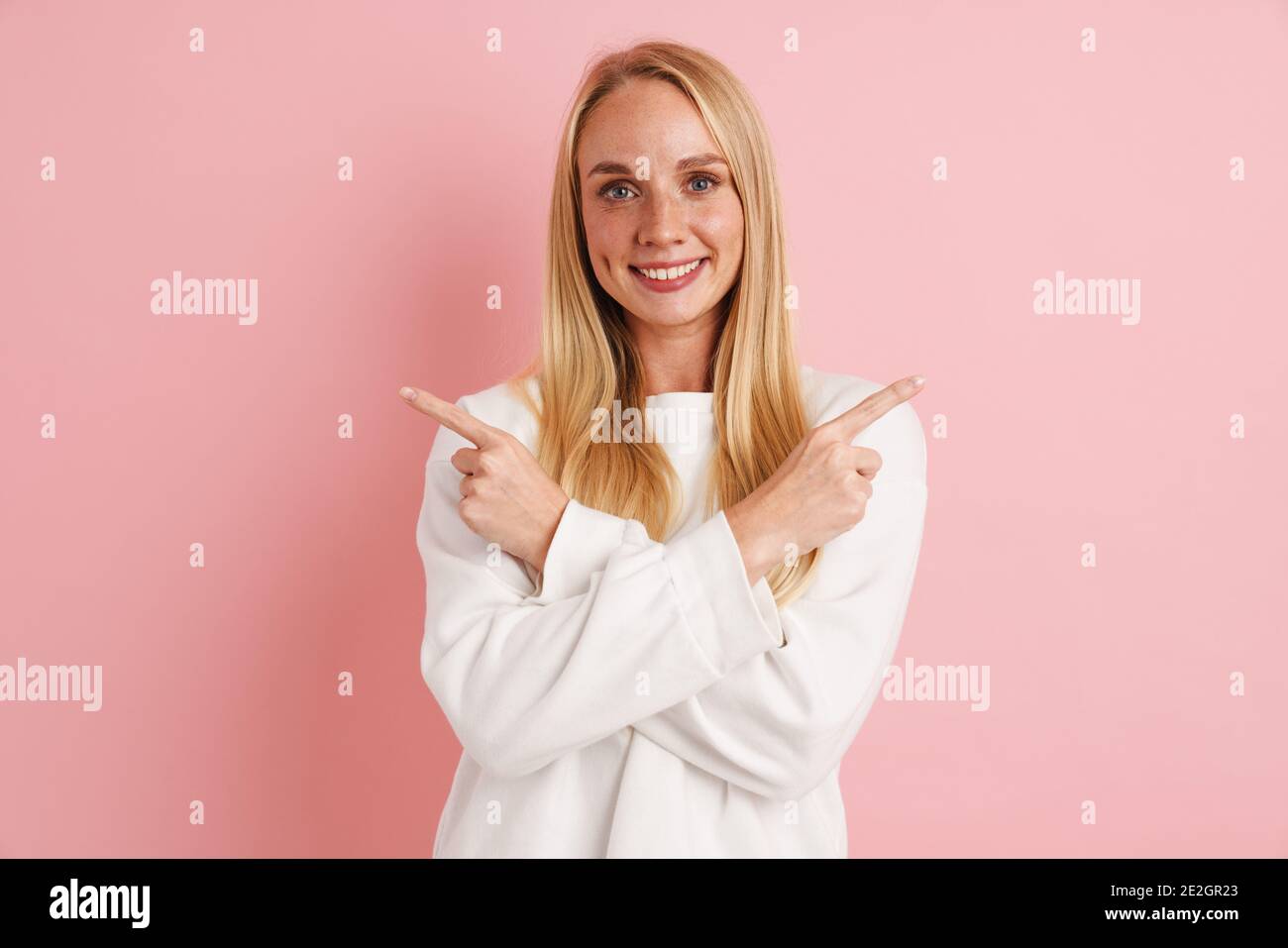 Happy beautiful girl smiling and pointing fingers at opposite ...