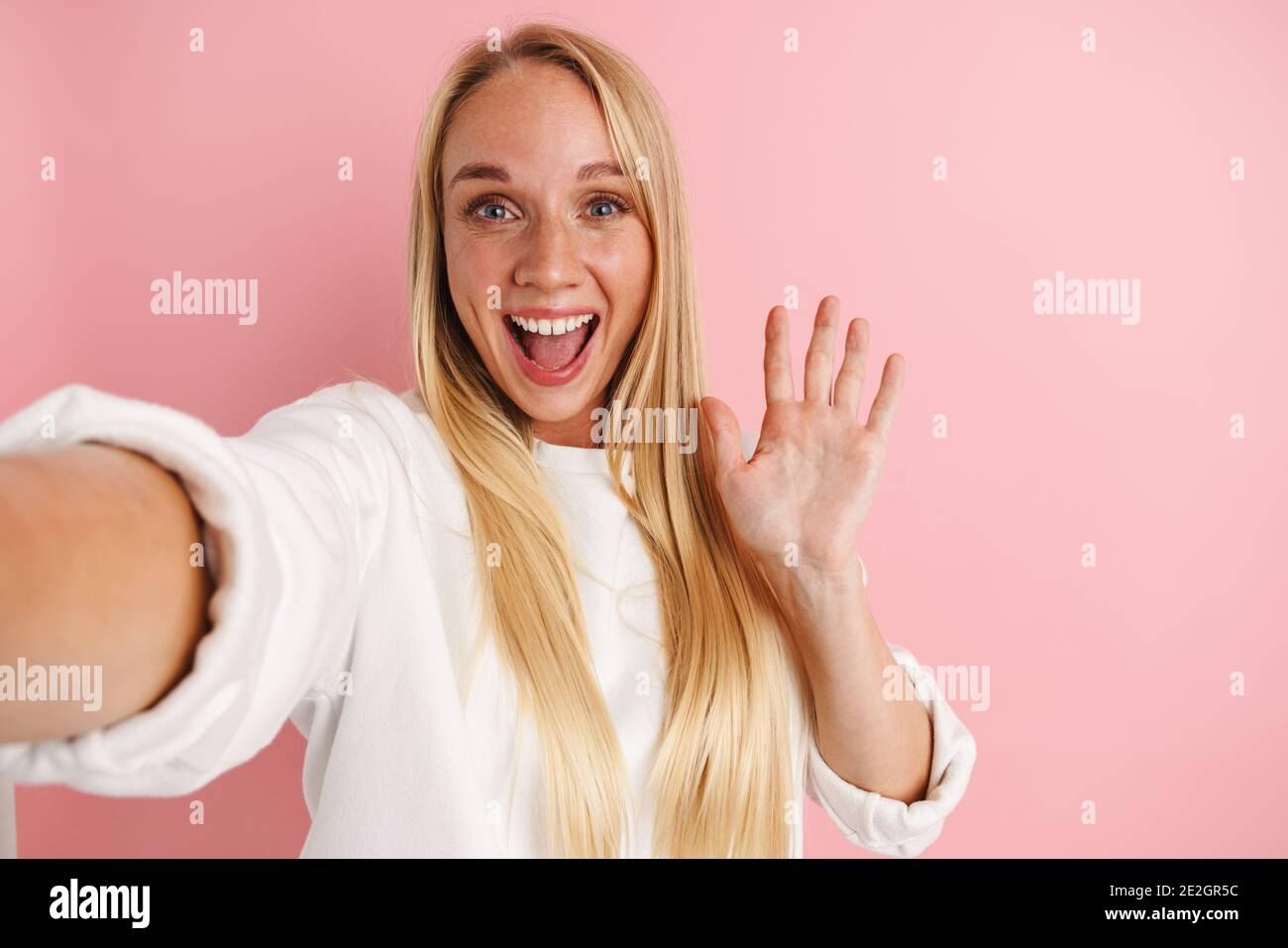 Joyful beautiful girl waving hand while taking selfie photo isolated ...
