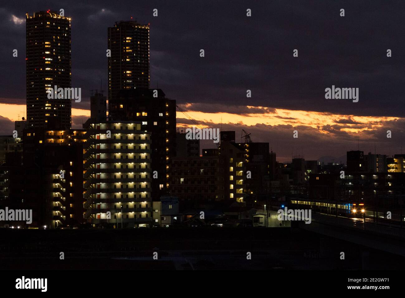 Sunset light behind towering apartment buildings and a commuter train ...