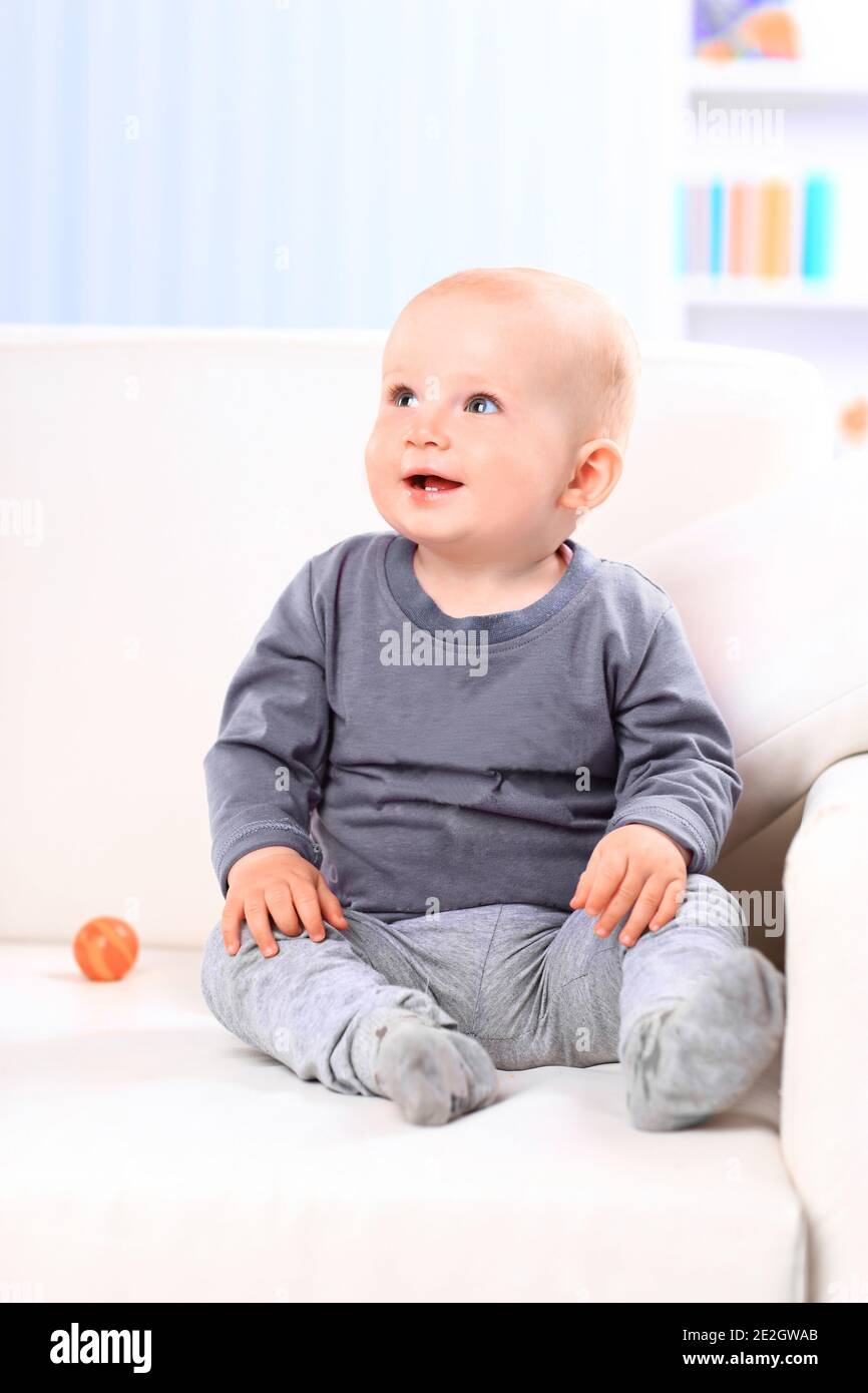 close up. pretty baby sitting on the home sofa Stock Photo - Alamy