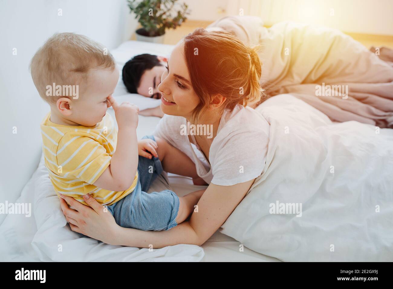 Mom talk with toddler in bed against the background of the father Stock ...