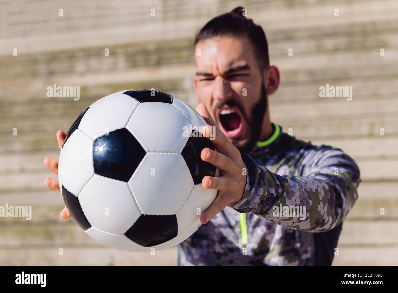 football ball in the hands of a sportsman screaming in a concrete ...