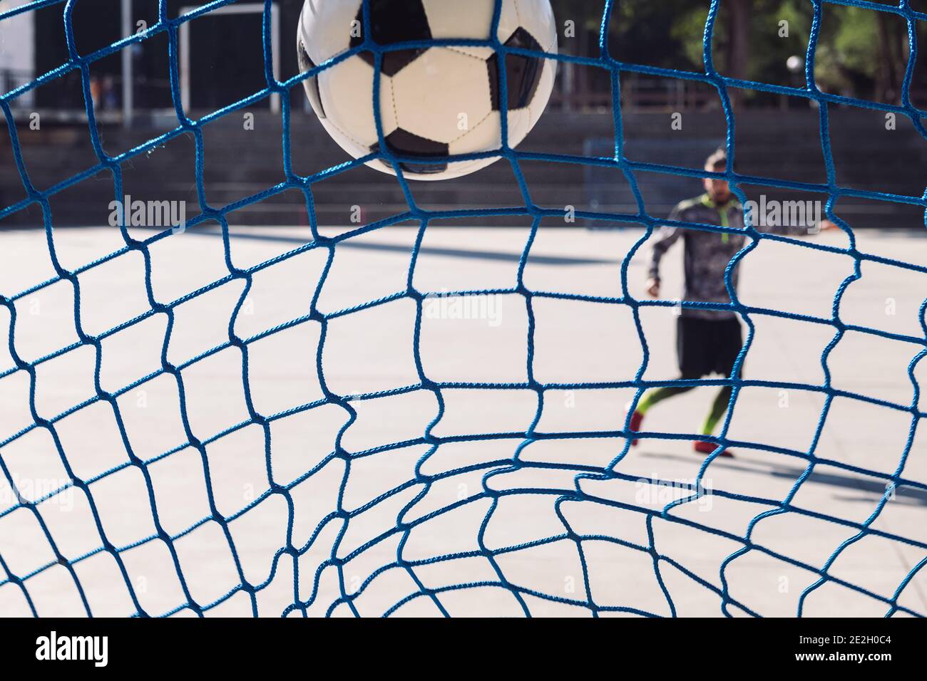 soccer ball hitting the goal net with an unfocused football player in ...