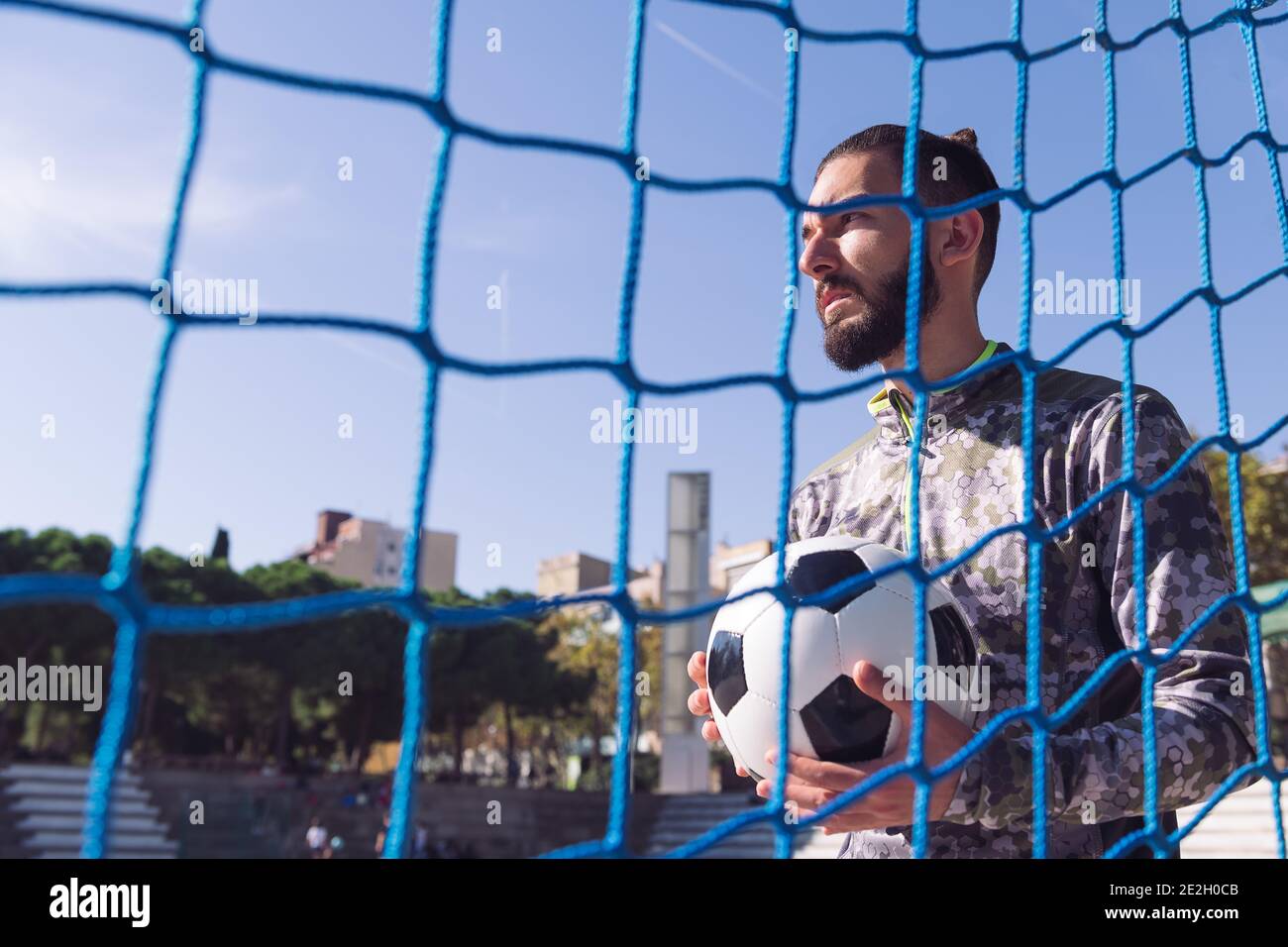 handsome football player through the goal net with the soccer ball in ...