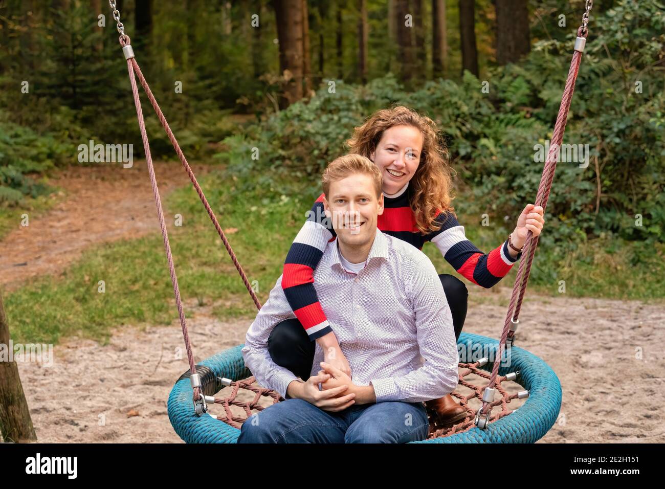 Young couple swings in the playground. the man and wife are in love ...