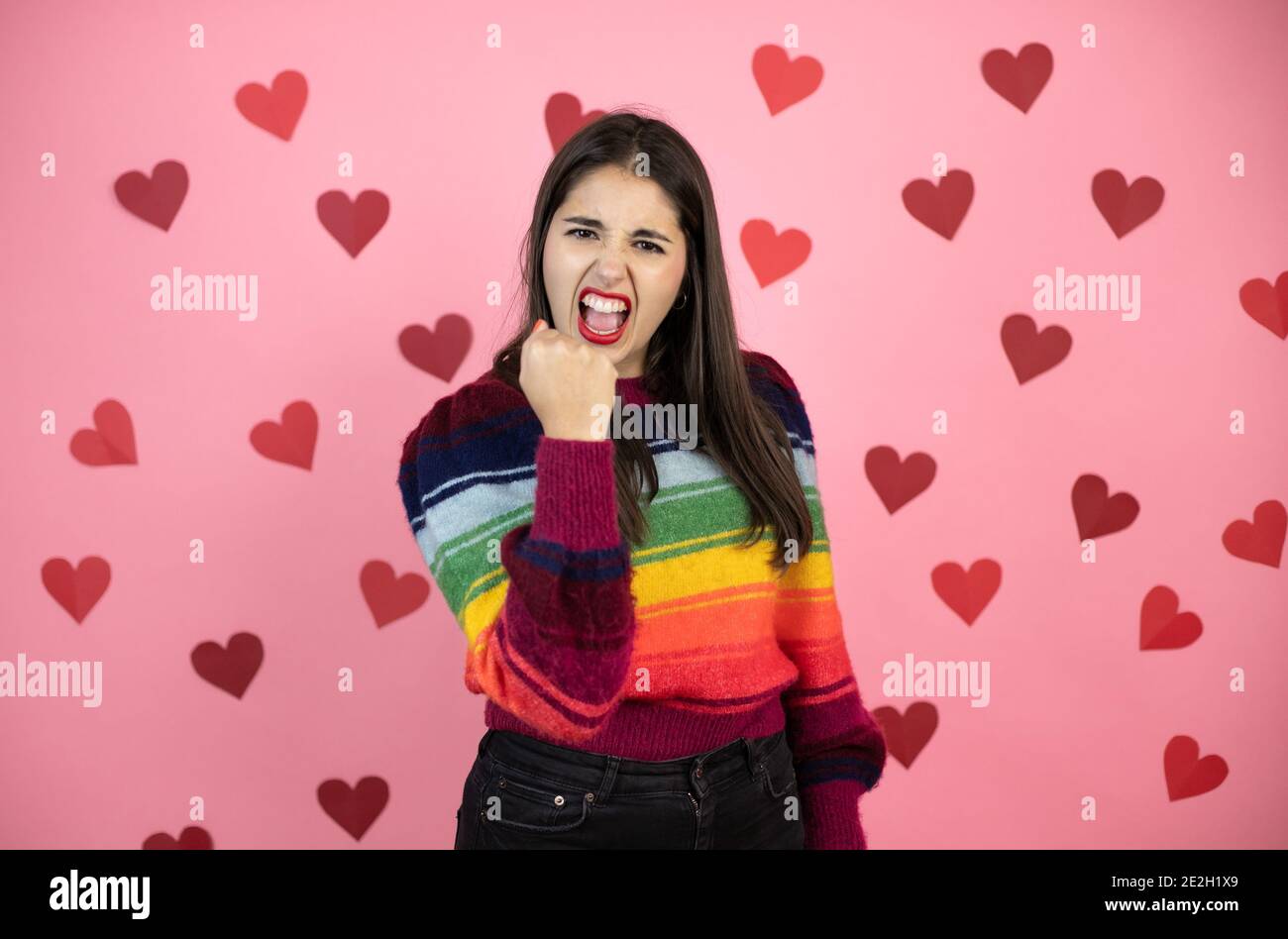 Young beautiful woman over pink background with harts angry and mad ...