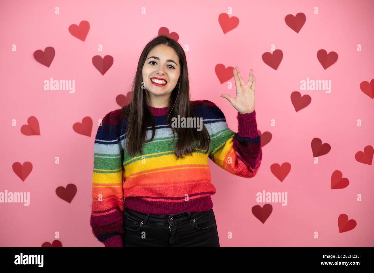 Young beautiful woman over pink background with harts doing star trek ...