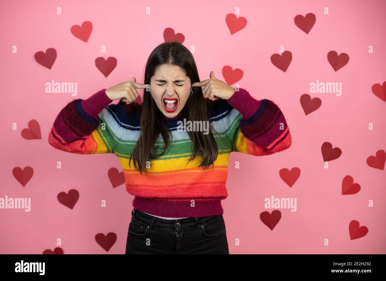 Young caucasian woman over pink background with red hearts covering ...