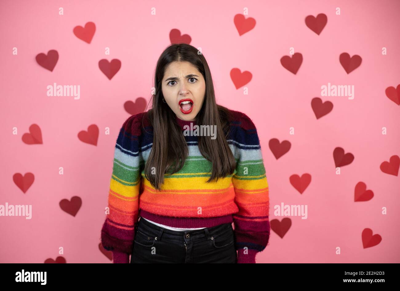 Young beautiful woman over pink background with harts afraid and ...