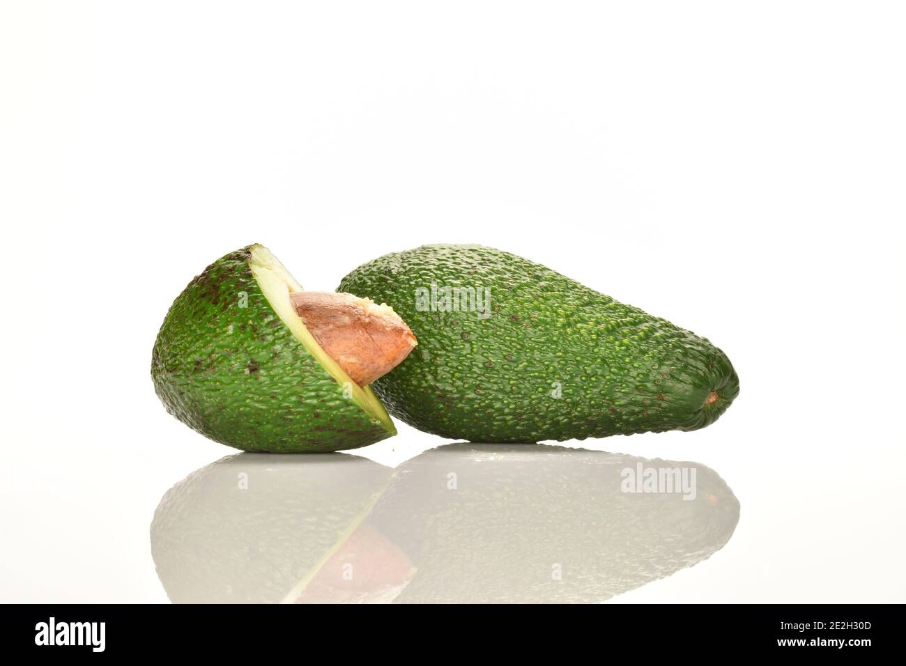 Half ripe juicy avocado with pitted and one whole dark green organic ...