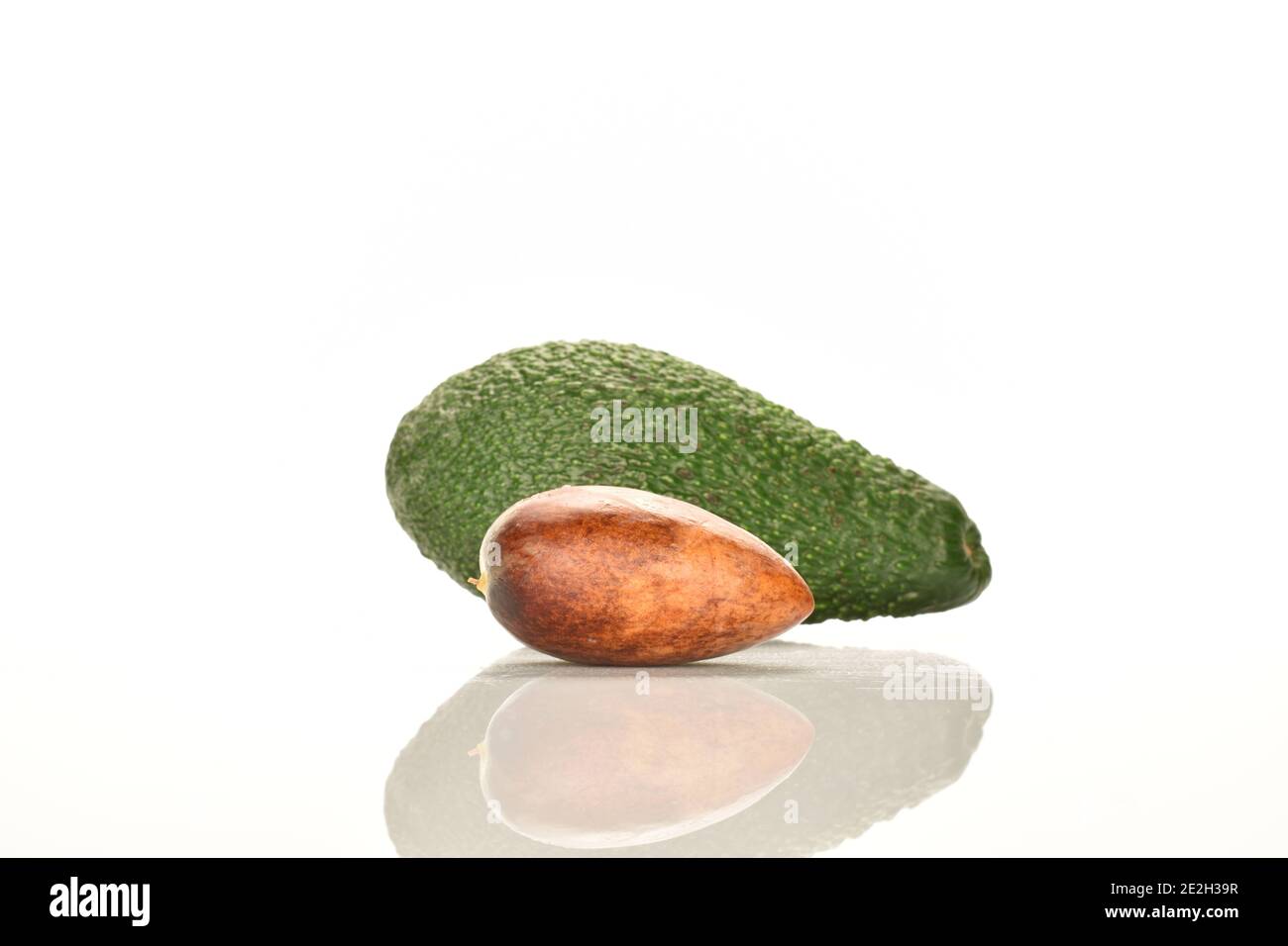 In the foreground, in focus, is one rounded whole brown avocado bone ...