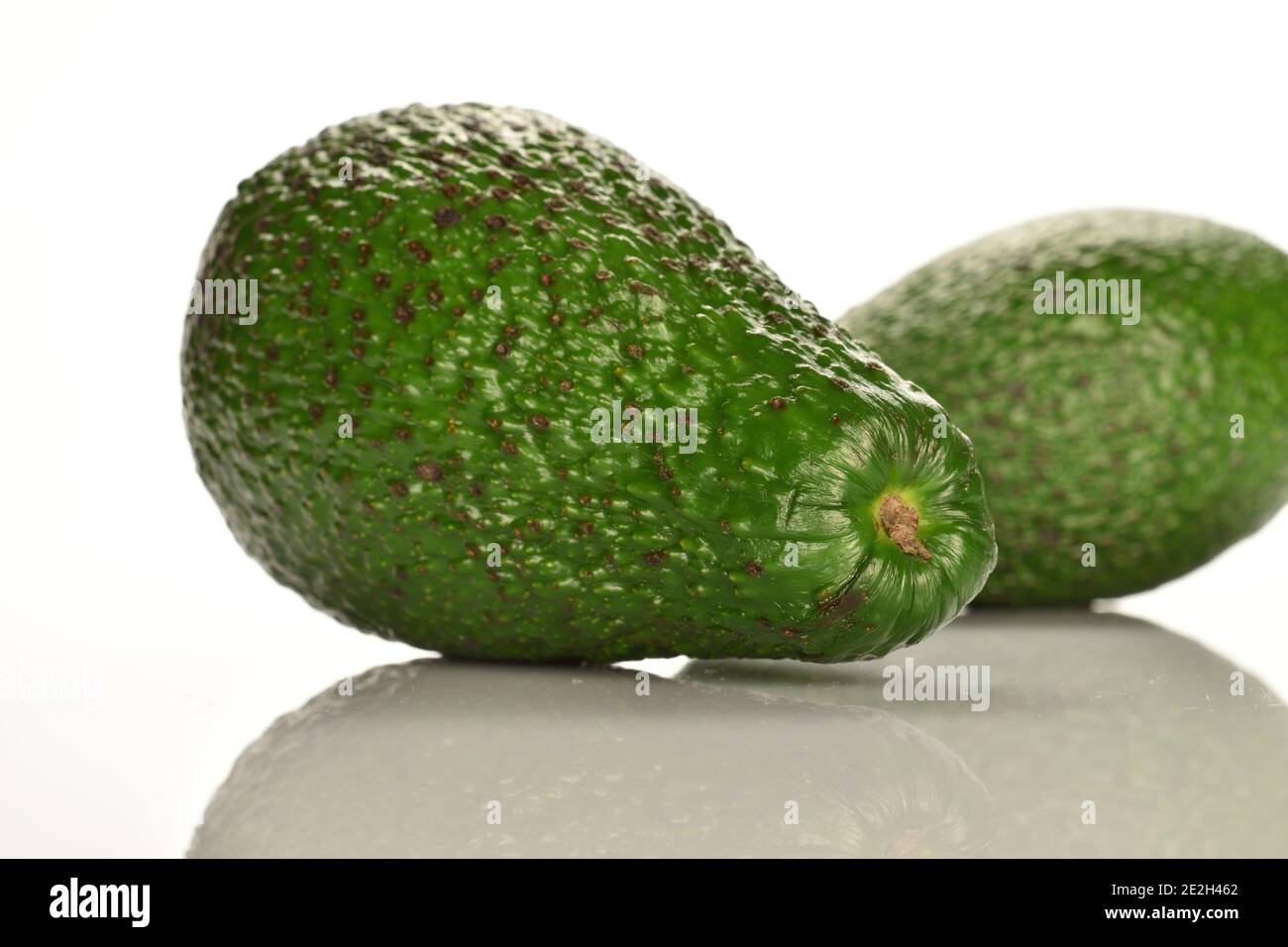 Two whole oval dark green ripe tasty diet avocados, lying one next to ...